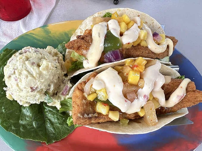 Fish tacos loaded with mango salsa and sauce, proving that handheld seafood is always a brilliant life choice.