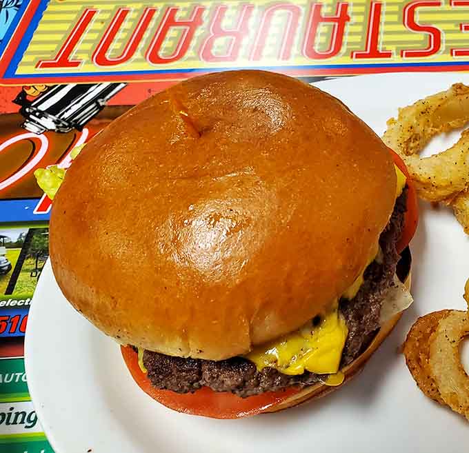 That cheeseburger sits tall and proud on a toasted bun, looking like it stepped out of a 1950s drive-in.