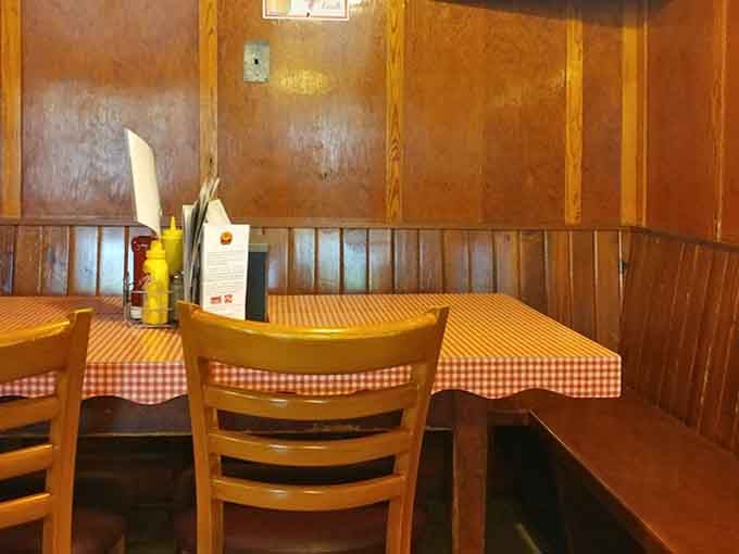 A cozy corner booth wrapped in warm wood paneling. This is the kind of seat you never want to leave.