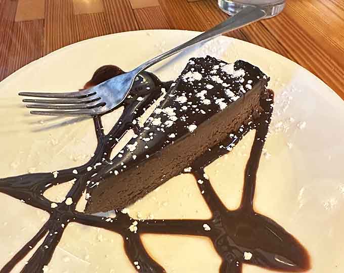 Chocolate cheesecake drizzled with enough chocolate sauce to make your dentist nervous but your soul absolutely delighted with life's choices.