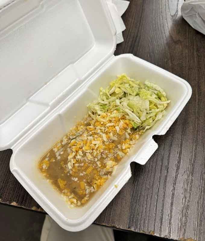 Green chile chicken enchilada swimming in sauce, topped with cheese and lettuce, looking like comfort food's greatest hits album.