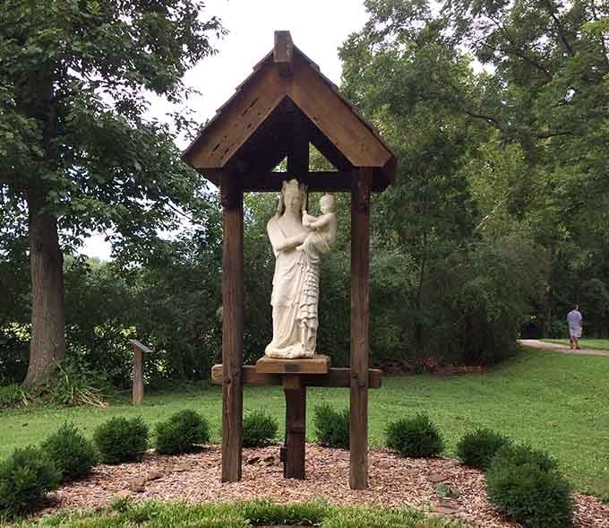 Our Lady and the Christ Child find shelter under a simple wooden canopy in the gardens.