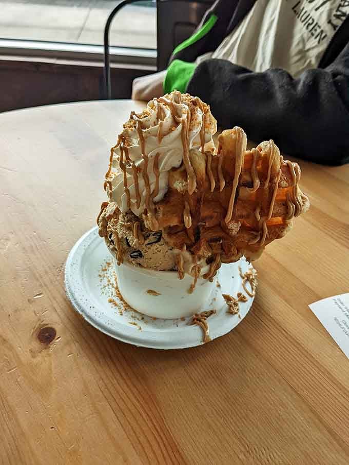 Waffle pieces, caramel drizzle, and a generous scoop make this creation look like dessert engineered by a very happy architect.