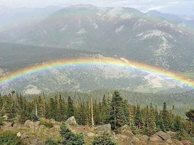 A full rainbow arcs across forested valleys, delivering that pot of gold moment without requiring any actual leprechaun negotiations whatsoever.