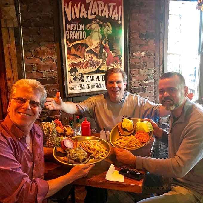 Three friends sharing plates beneath a vintage Marlon Brando poster, proving good food creates the best memories every time.