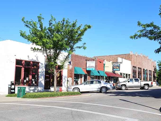 Storefronts wearing their history comfortably, where awnings provide actual shade and window shopping means something beyond scrolling screens endlessly.