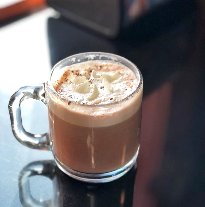 Hot cocoa topped with whipped cream and cocoa powder, because sometimes you need comfort in a mug.