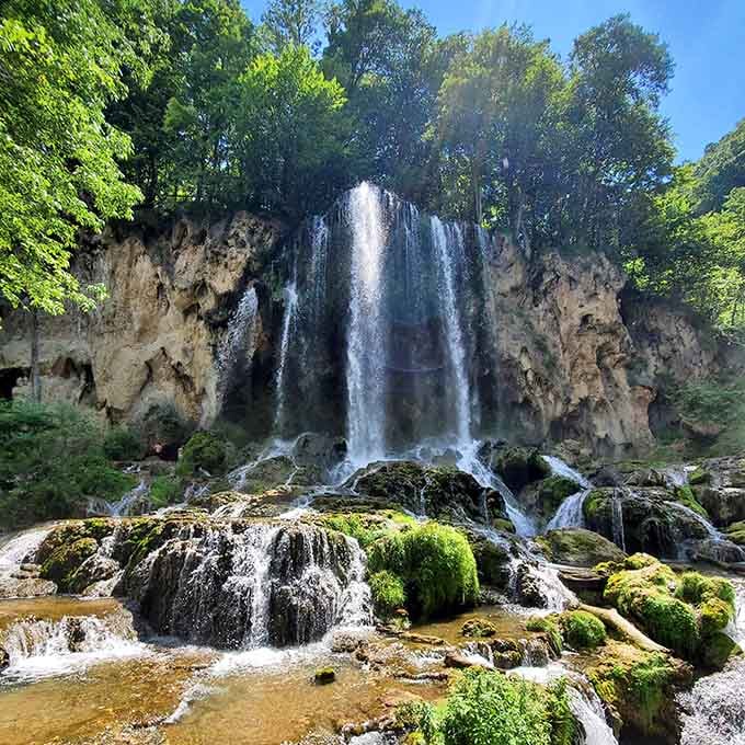 Majestic waterfall plummets from dramatic cliff creating thunderous spray and misty magic in lush surroundings.