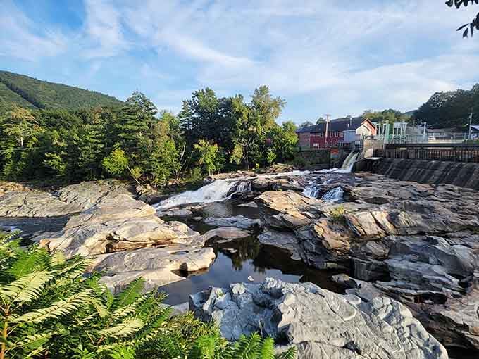 Water rushing over sculpted rock while a charming village watches from the hillside in Shelburne Falls.