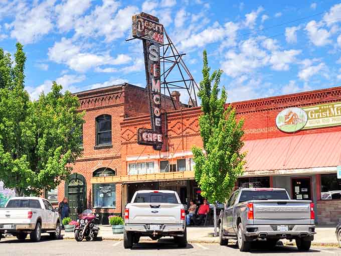 That vintage neon sign towers over brick buildings like a beacon calling travelers to stop and explore this gem.