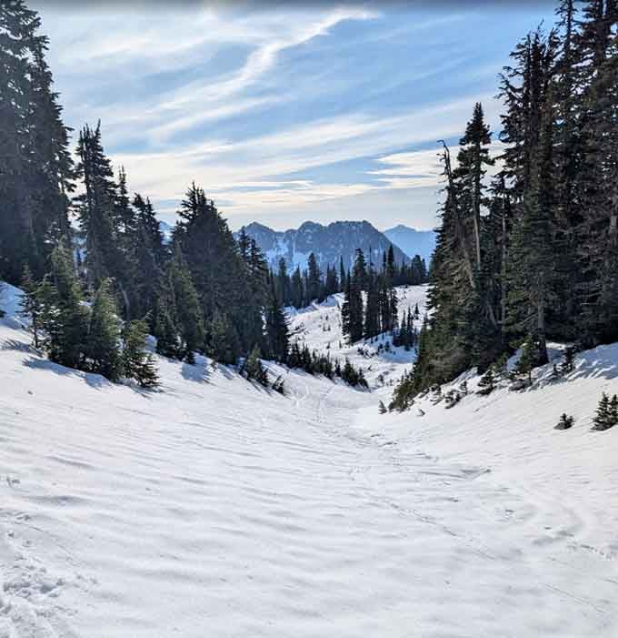 Snow blankets the mountain trail where winter transforms the landscape into a pristine wonderland of white.