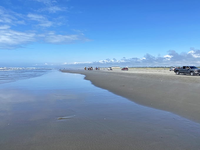 Rocky shores meet endless ocean where waves gently kiss the stones beneath a brilliant sky.