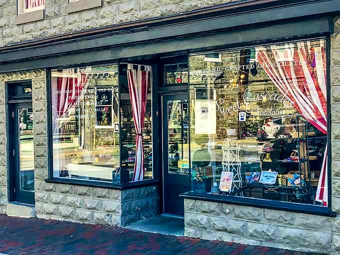 Those red-and-white striped curtains frame windows filled with handcrafted chocolates like a stage set for sweet temptation.