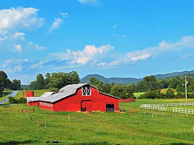 That classic red barn against green pastures and mountain backdrop could be a postcard from simpler, sweeter times.