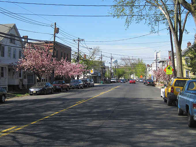 Spring blossoms frame quiet streets where neighbors still know each other's names and wave from their porches.