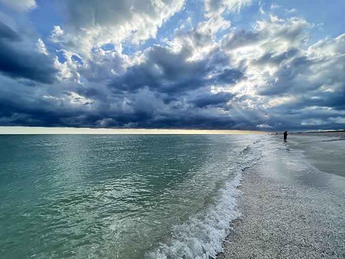 Storm clouds gather dramatically over turquoise shallows, creating a spectacular light show that reminds us nature's the ultimate artist.