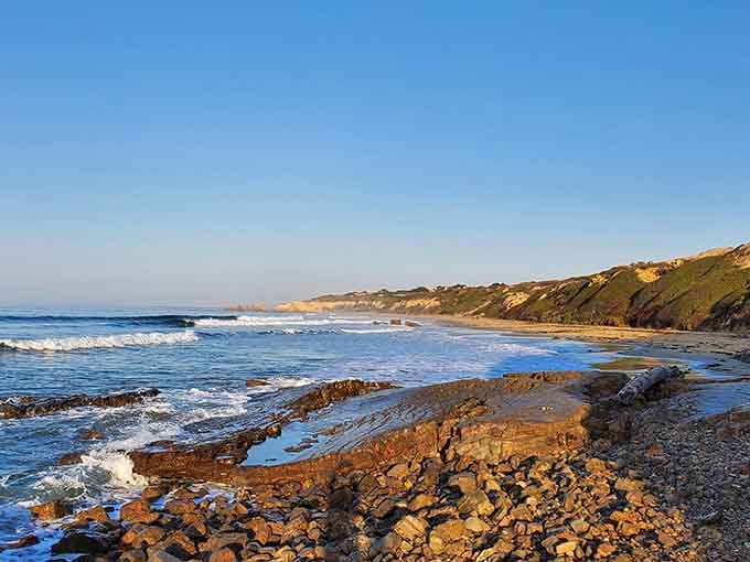 Rocky outcrops frame gentle waves along this secluded stretch where nature still calls all the shots beautifully.