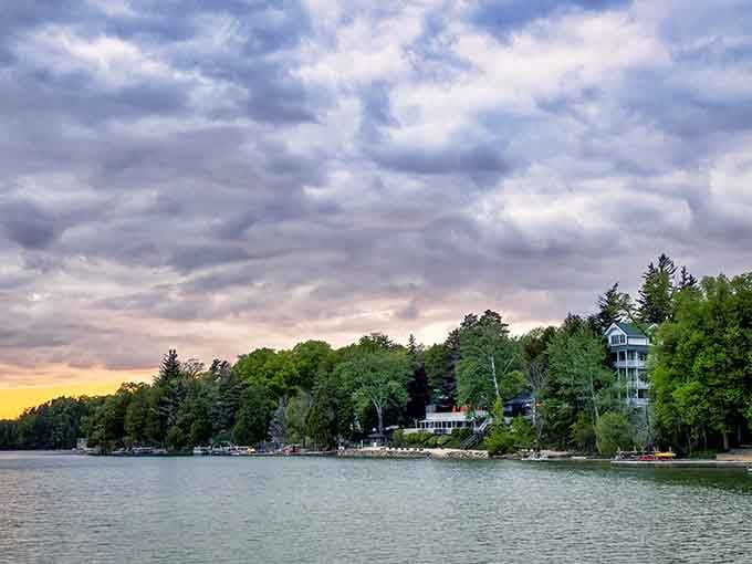 Elkhart Lake's shoreline glows at sunset, where dramatic clouds paint the sky in shades of gold and lavender.