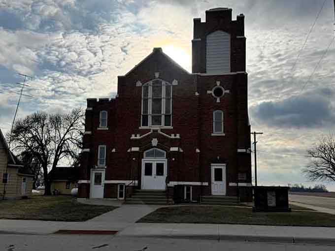 Louisburg's dark brick church rises against a dramatic winter sky, its tall tower cutting through the clouds like a bold exclamation point.