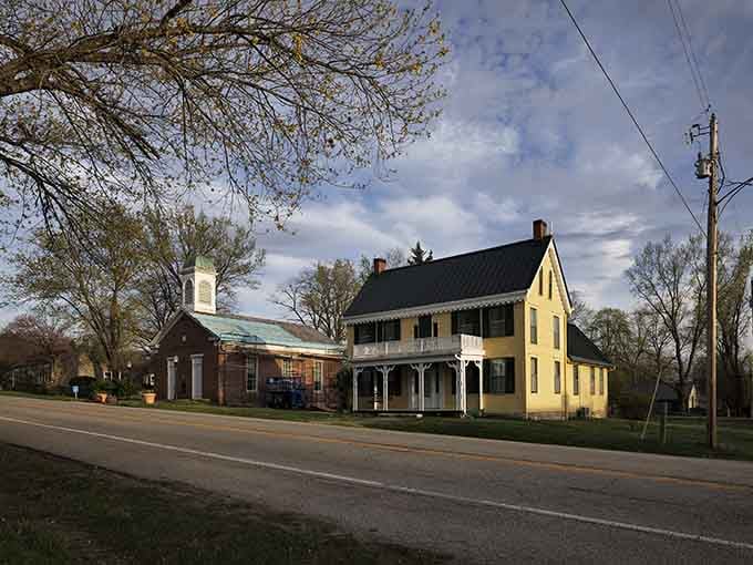 That butter-yellow colonial house with dark shutters looks like it stepped straight from a history book's most charming chapter.