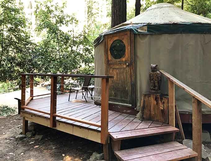 A wooden deck, a carved owl guardian, and a yurt with a porthole door. Tolkien would approve.