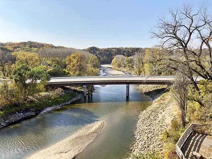 The Blue Earth River winds beneath this century-old bridge like a liquid highway through time itself.