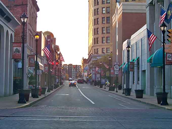 Golden hour transforms downtown into a postcard where American flags wave proudly above brick buildings that remember better days.