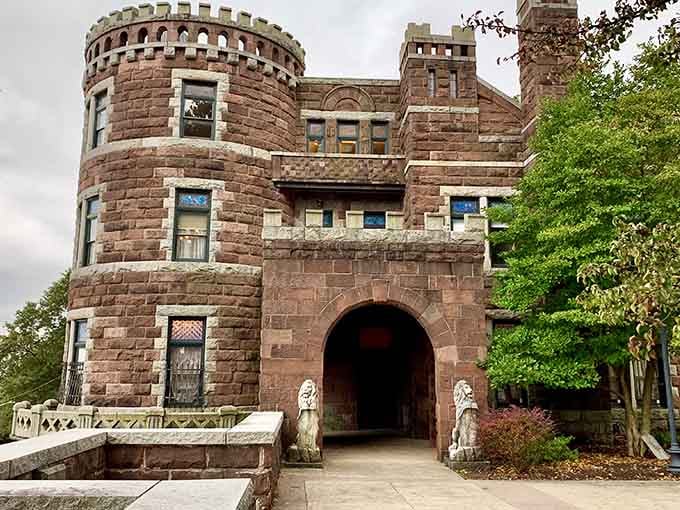 Warm reddish-brown stone, crenellated roofline, and enough architectural detail to make your jaw forget its job.