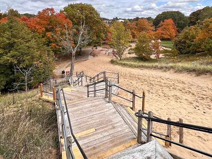 The boardwalk winds through fall colors like a wooden ribbon leading to sandy paradise below.