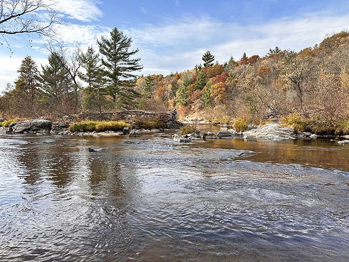 Fall colors frame the Eau Claire River as it flows peacefully through Big Falls County Park, creating a stunning seasonal display.
