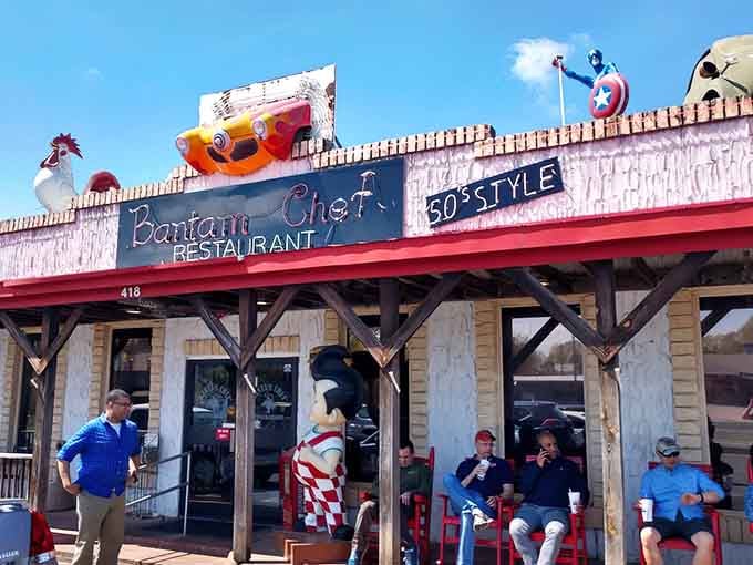 Friendly locals gather outside the vibrant storefront, where quirky rooftop decor and classic statues set a fun, welcoming mood.