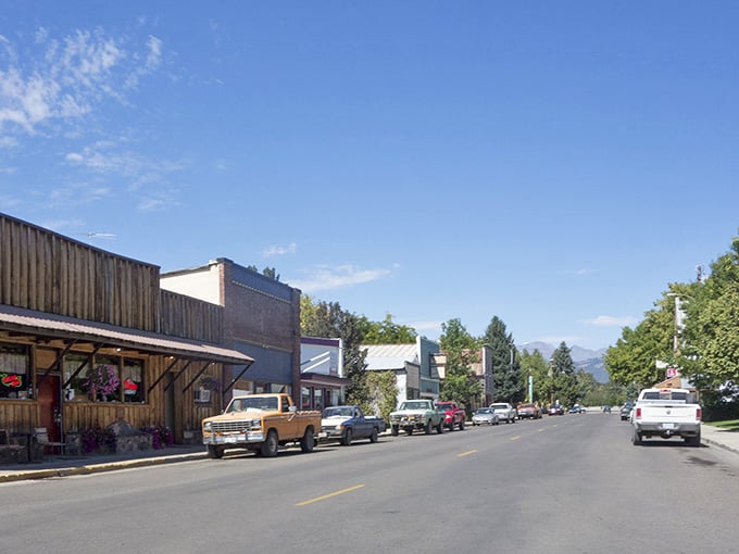 Wooden storefronts, angle-parked pickups, and snow-capped mountains framing the street like a postcard nobody bothered to sell.