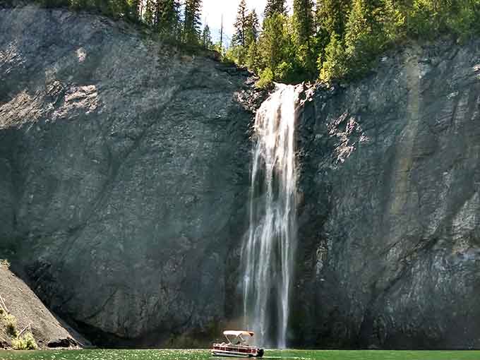 A pontoon boat sits at the base of Peewee Falls, looking about as significant as a rubber duck in a bathtub.