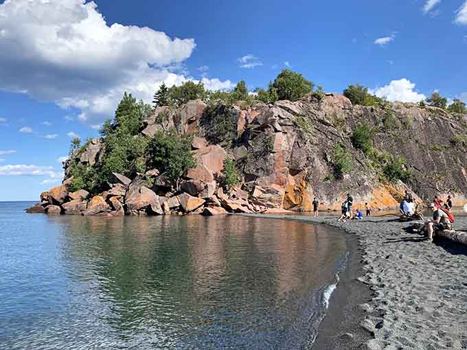 Ancient red cliffs meet black sand and sparkling Superior water in one jaw-dropping Minnesota scene.