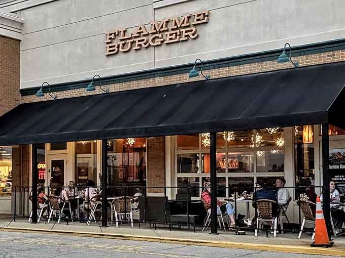 That black awning and warm glow spilling onto the patio tell you everything you need to know about Flamme Burger.