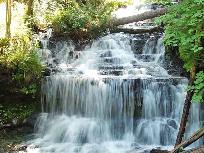 Sunlight, mist, and mossy rock shelves combine at Wagner Falls into something genuinely unforgettable.