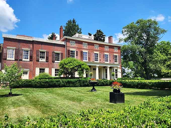 This grand Federal-style brick mansion sits under a blue sky like it owns the whole neighborhood, because it basically does.