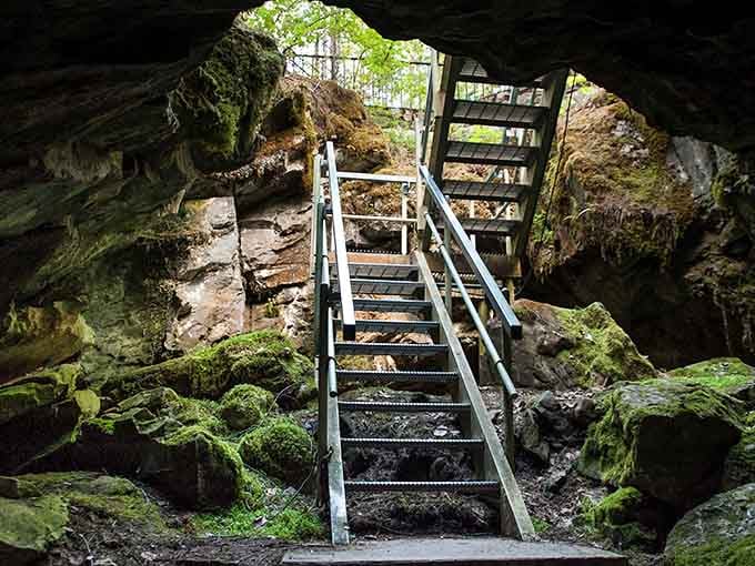 Nature's own doorway, where moss-covered rocks and metal stairs dare you to step inside.
