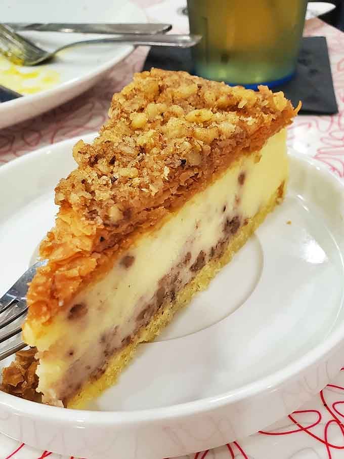 A thick slice of crumble-topped cheesecake that looks like it was made with genuine Sunday afternoon dedication.