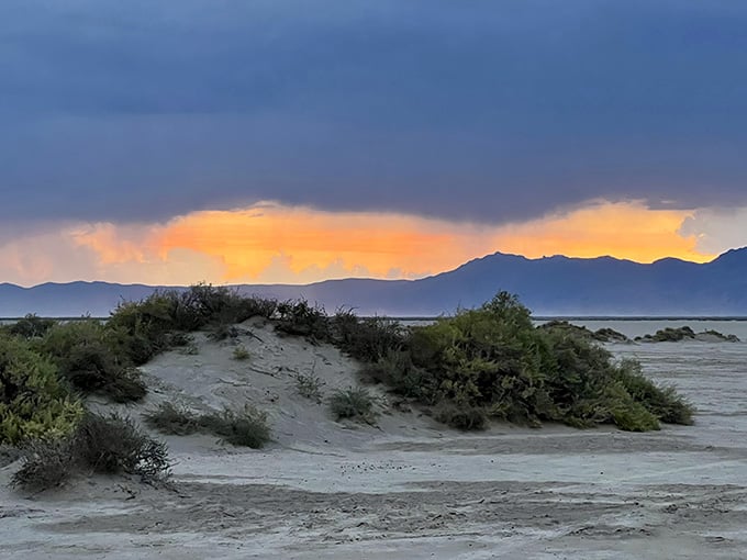 Storm clouds part like theater curtains, revealing mountains backlit by nature's own spotlight in shades of tangerine and gold.