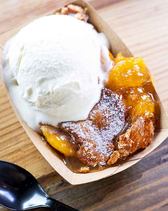 Warm peach cobbler topped with a generous scoop of vanilla ice cream. Dessert doesn't get more honest than this.
