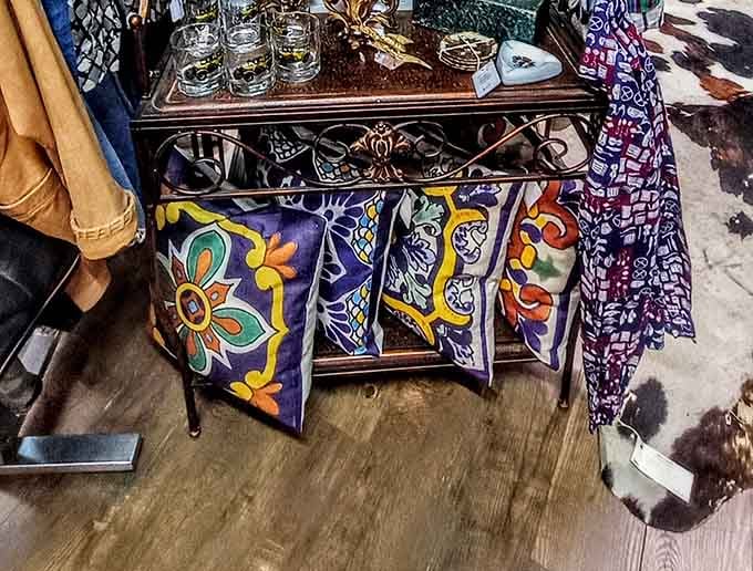 Bold Talavera-style decorative pillows hanging from a wrought iron rack, bringing serious color to an already lively corner of the mall.