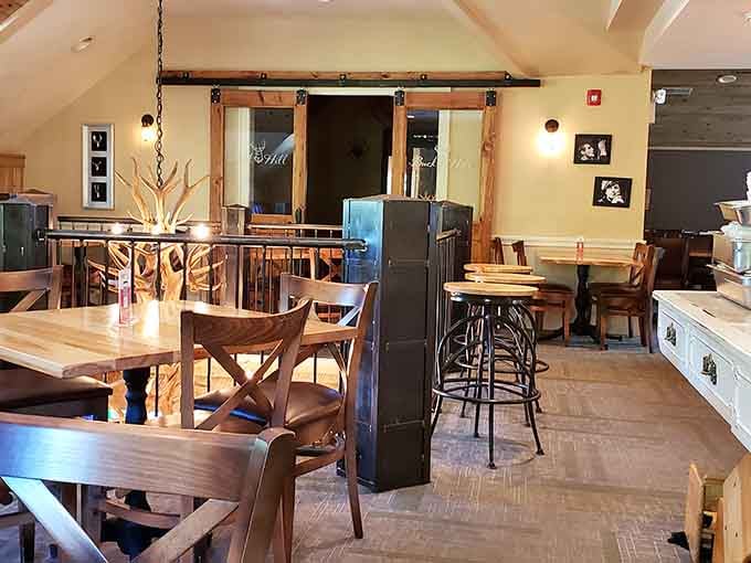 Barn doors, antler chandeliers, and rustic charm — this upper dining room feels like a very well-fed hunting lodge.