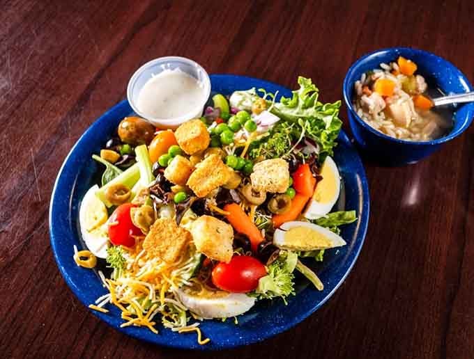 A loaded house salad with a bowl of soup on the side, proof that the Butter Churn covers all the bases.