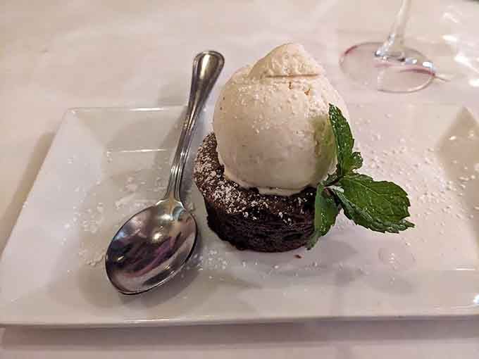 A chocolate lava cake crowned with ice cream, a fresh mint sprig, and a dusting of powdered sugar. That spoon isn't going to use itself.
