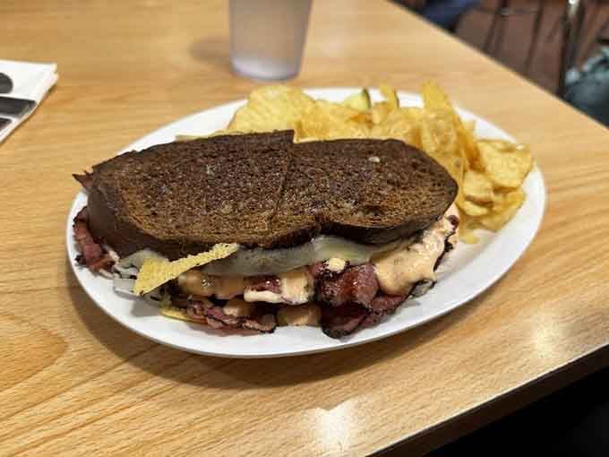 The Russian Reuben arrives stacked and confident on grilled dark rye, with chips on the side for good measure.
