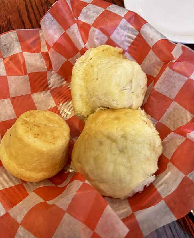 Fluffy biscuits and a golden corn muffin tucked into checkered paper. The bread basket here deserves its own standing ovation.
