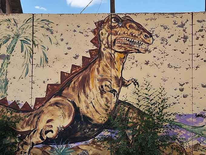 This weathered wall mural roars with personality, a T-Rex frozen mid-strut against a desert backdrop.