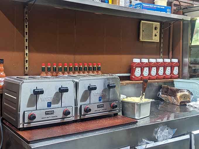 Two heavy-duty toasters, rows of hot sauce, and bread on standby, a kitchen that means serious business around the clock.