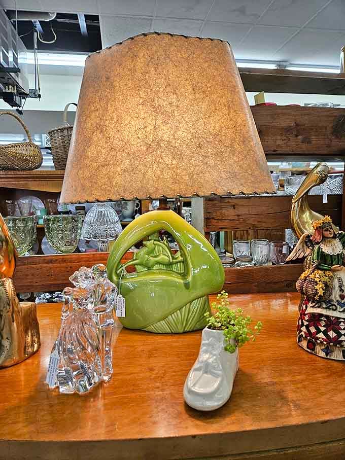 A green ceramic lamp with a parchment shade sits among crystal figurines, radiating serious mid-century living room energy.